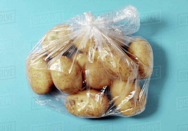 Bunch of potatoes packed in plastic bag over colored background - Stock ...