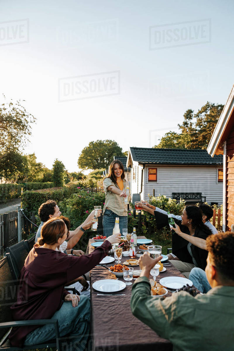 Happy young woman doing celebratory toast with male and female friends ...