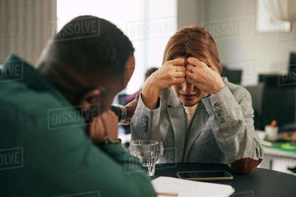 Male business professional consoling crying female colleague in office ...