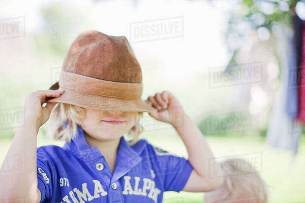 Boy pulling hat over face - Stock Photo - Dissolve