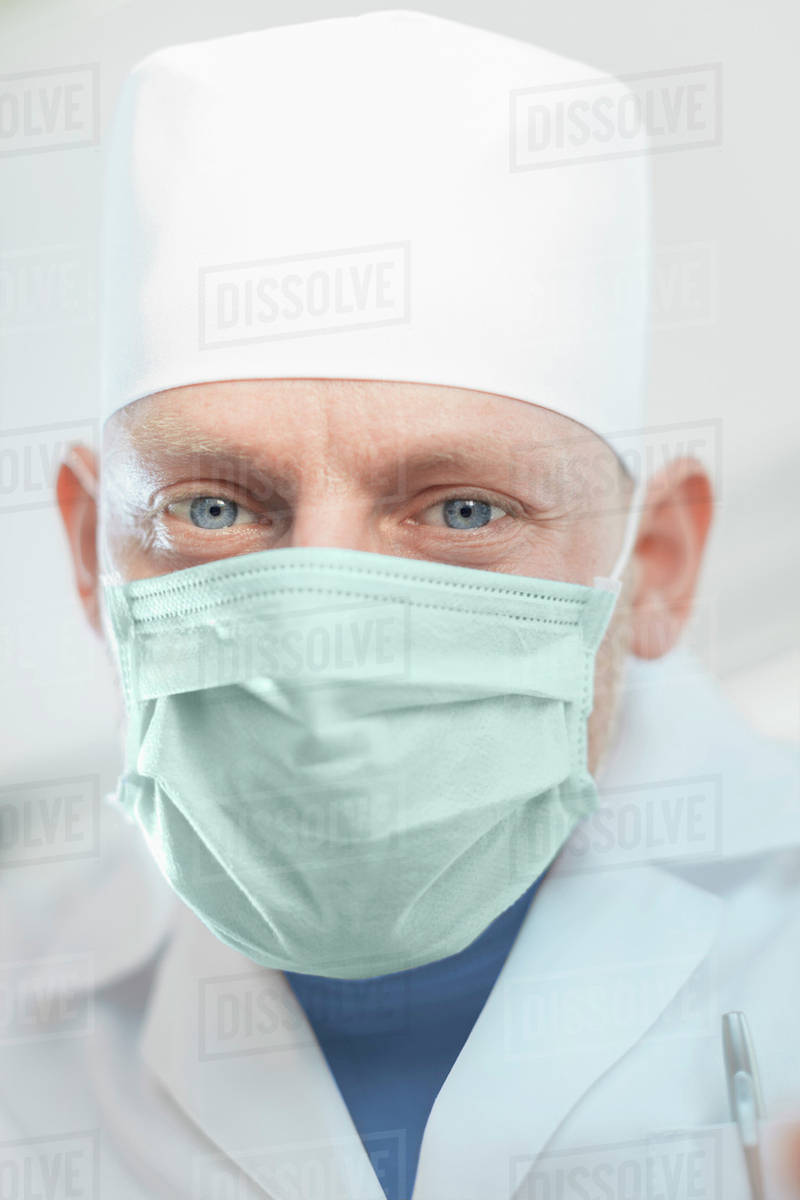 Portrait of a mature doctor wearing surgical mask - Stock Photo - Dissolve