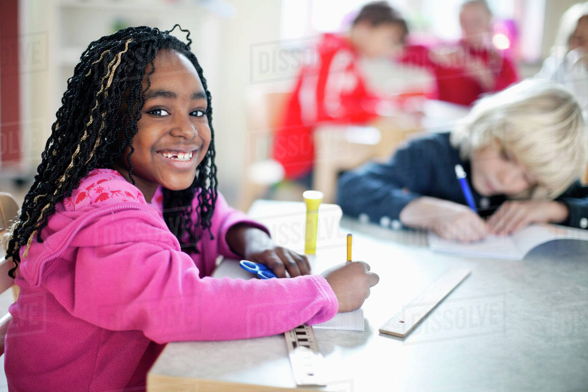 Portrait of smiling girl writing with friends in the background - Stock ...