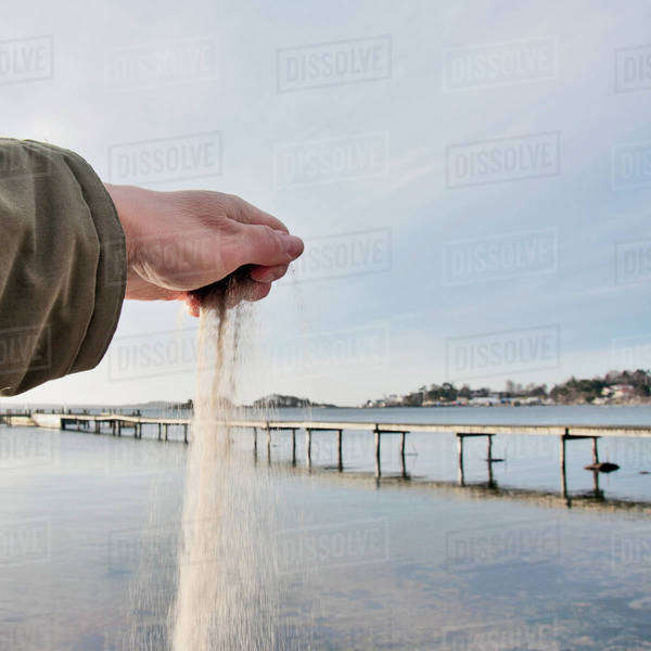 Sand slipping through fist - Stock Photo - Dissolve
