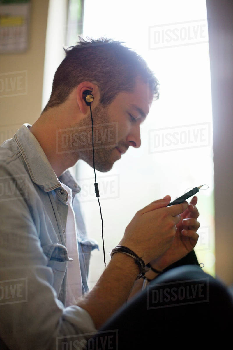 Side view of young man listening music through cell phone - Royalty ...