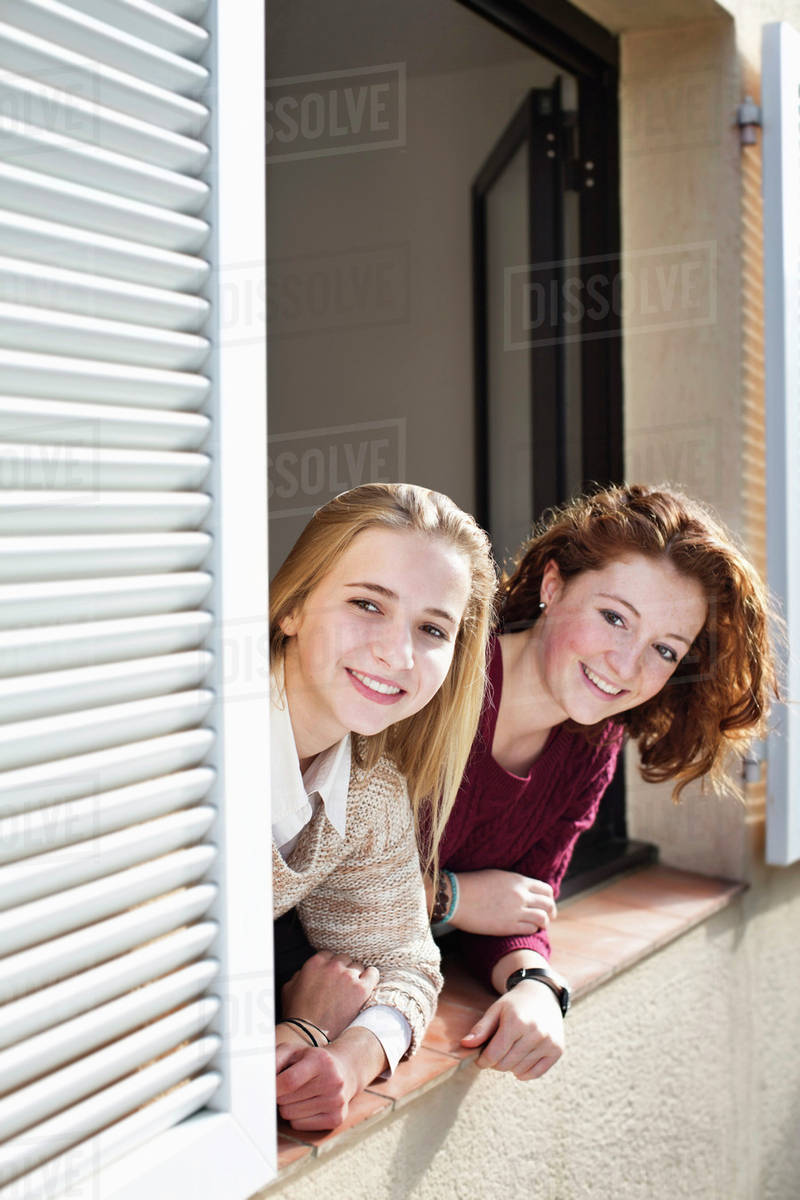 Happy young female friends looking through house window - Stock Photo ...