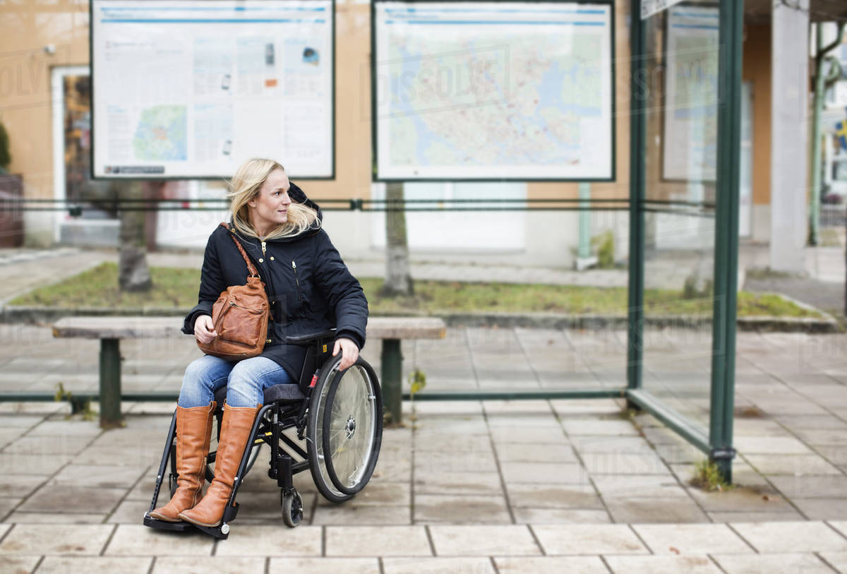 Disabled woman in wheelchair waiting at bus stop - Royalty-free Stock ...