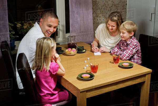 Happy family playing dice game at home - Stock Photo - Dissolve