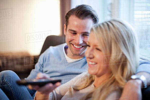 Mid adult man looking at woman watching TV - Royalty-free Stock Photo ...