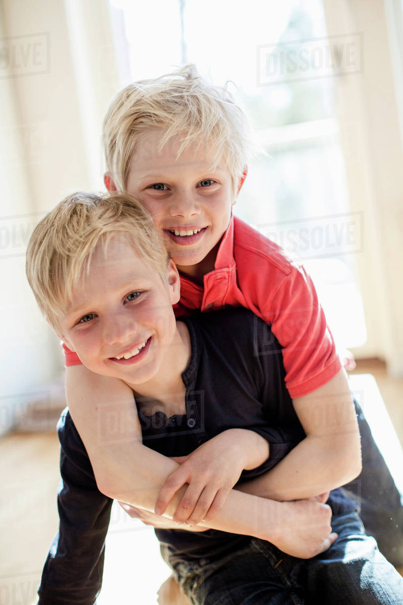 Portrait of boy embracing brother from behind in house - Royalty-free ...
