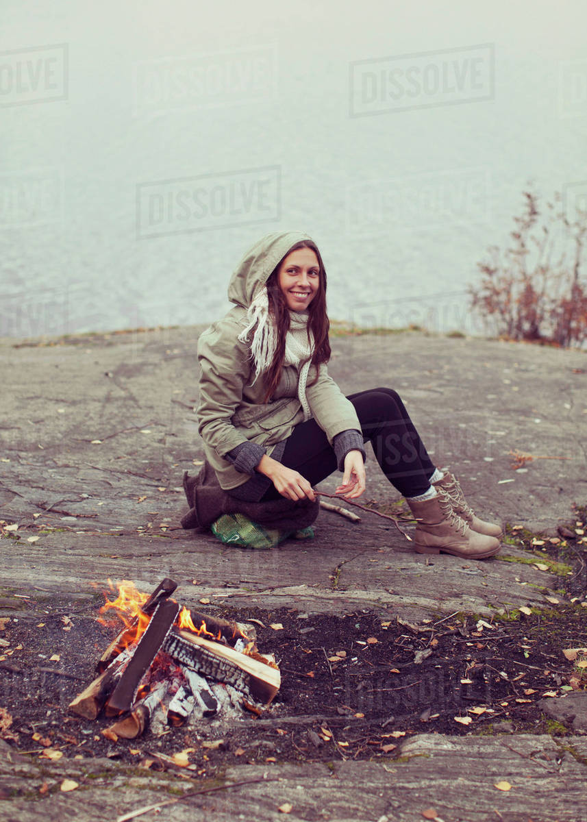 Full length of woman holding stick by campfire at lakeshore - Royalty ...
