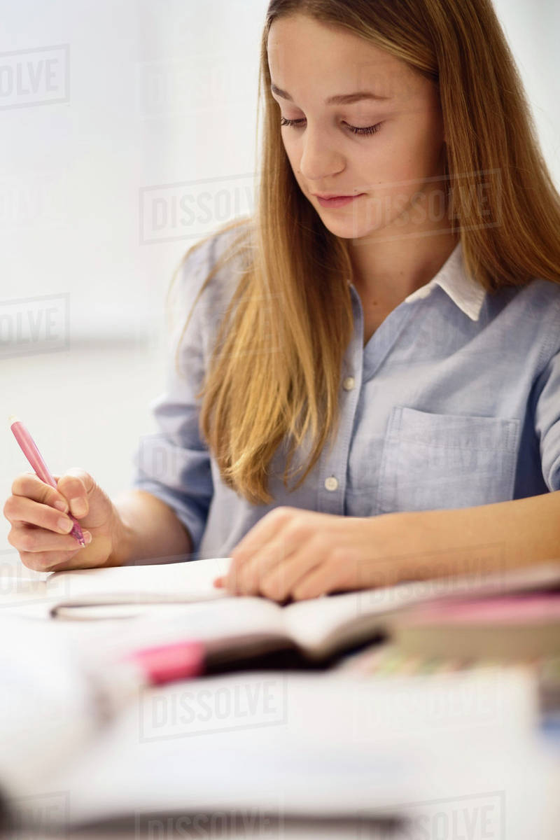 High school girl studying at desk in classroom - Stock Photo - Dissolve