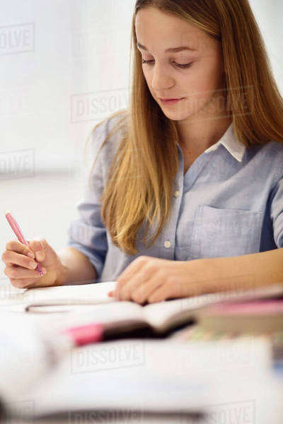 High school girl studying at desk in classroom - Stock Photo - Dissolve