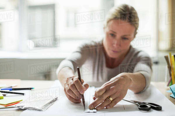 Businesswoman drawing line using ruler on paper - Stock Photo - Dissolve