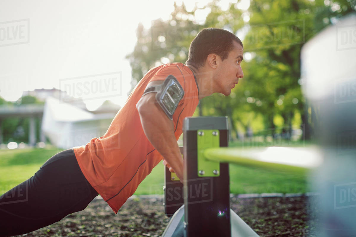 Side view of man doing push-ups on railing at park - Royalty-free Stock ...