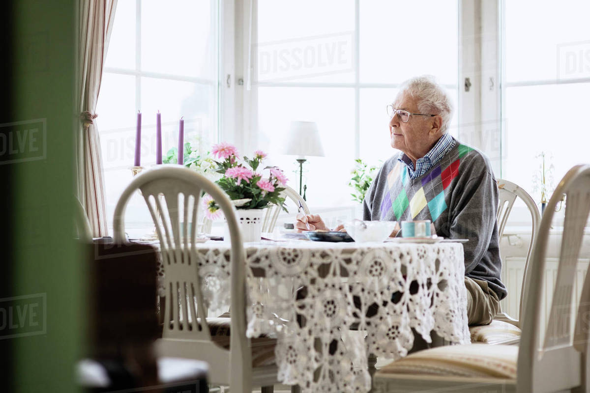 Thoughtful senior man sitting on dining table at nursing home - Royalty ...