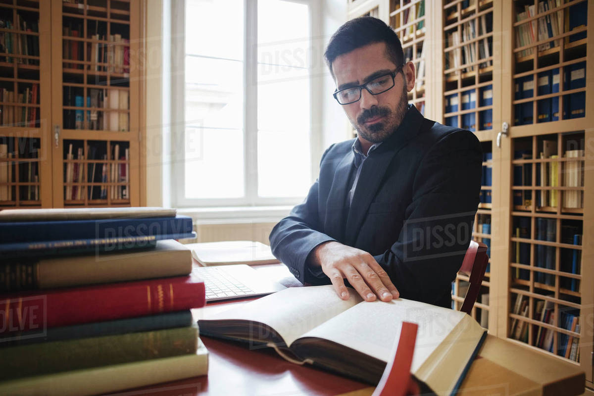 Serious professional reading book while sitting in law library ...