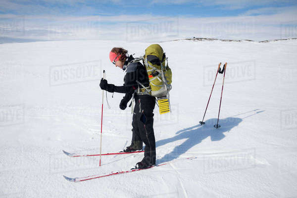 Full length of mature female skier with backpack on snow covered ...