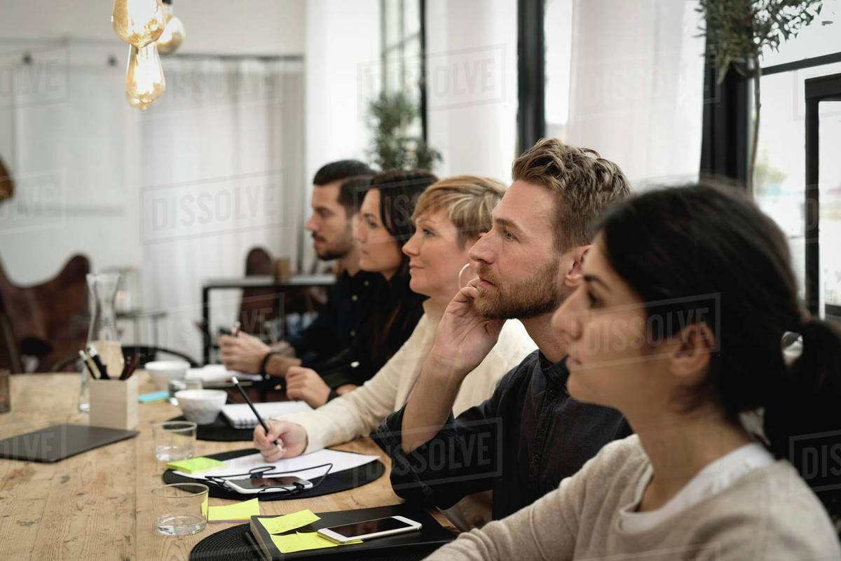 Side view of business people sitting at table in office - Stock Photo ...