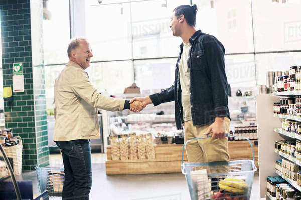 Happy men shaking hands in supermarket - Royalty-free Stock Photo ...