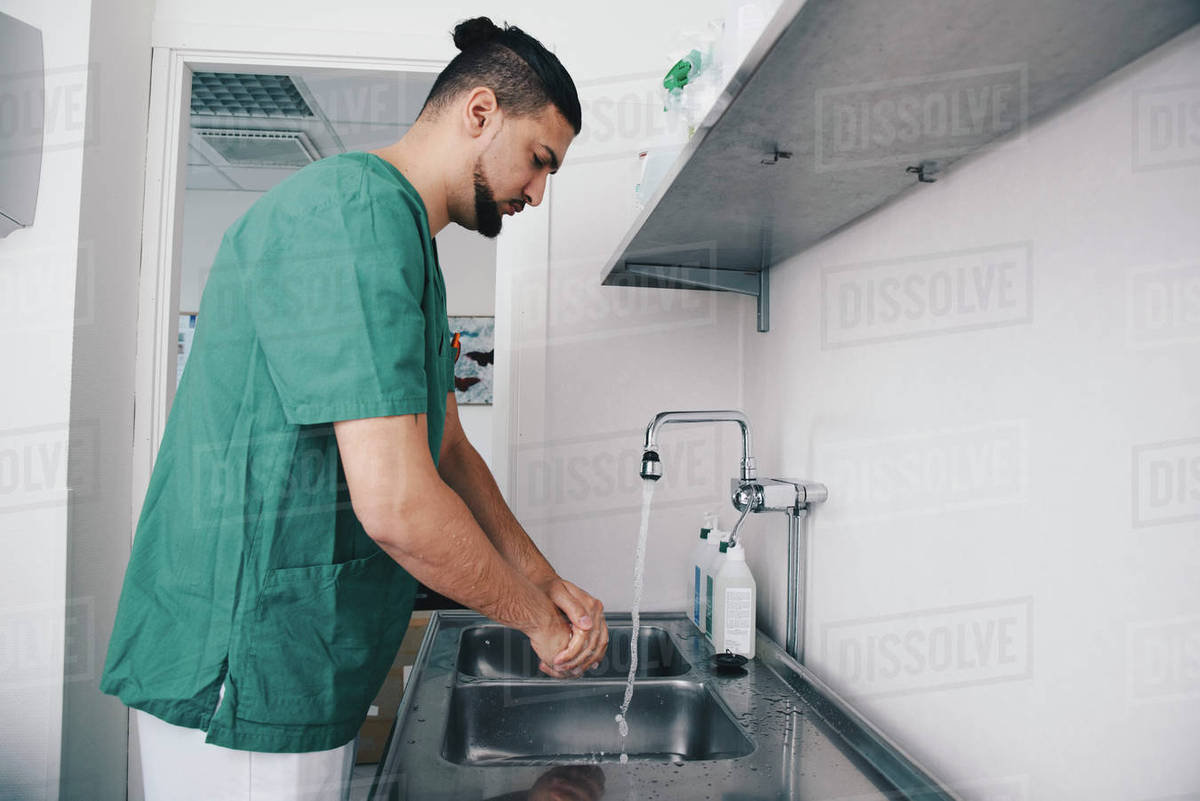 Side view of male nurse washing hands in sink at hospital - Royalty ...