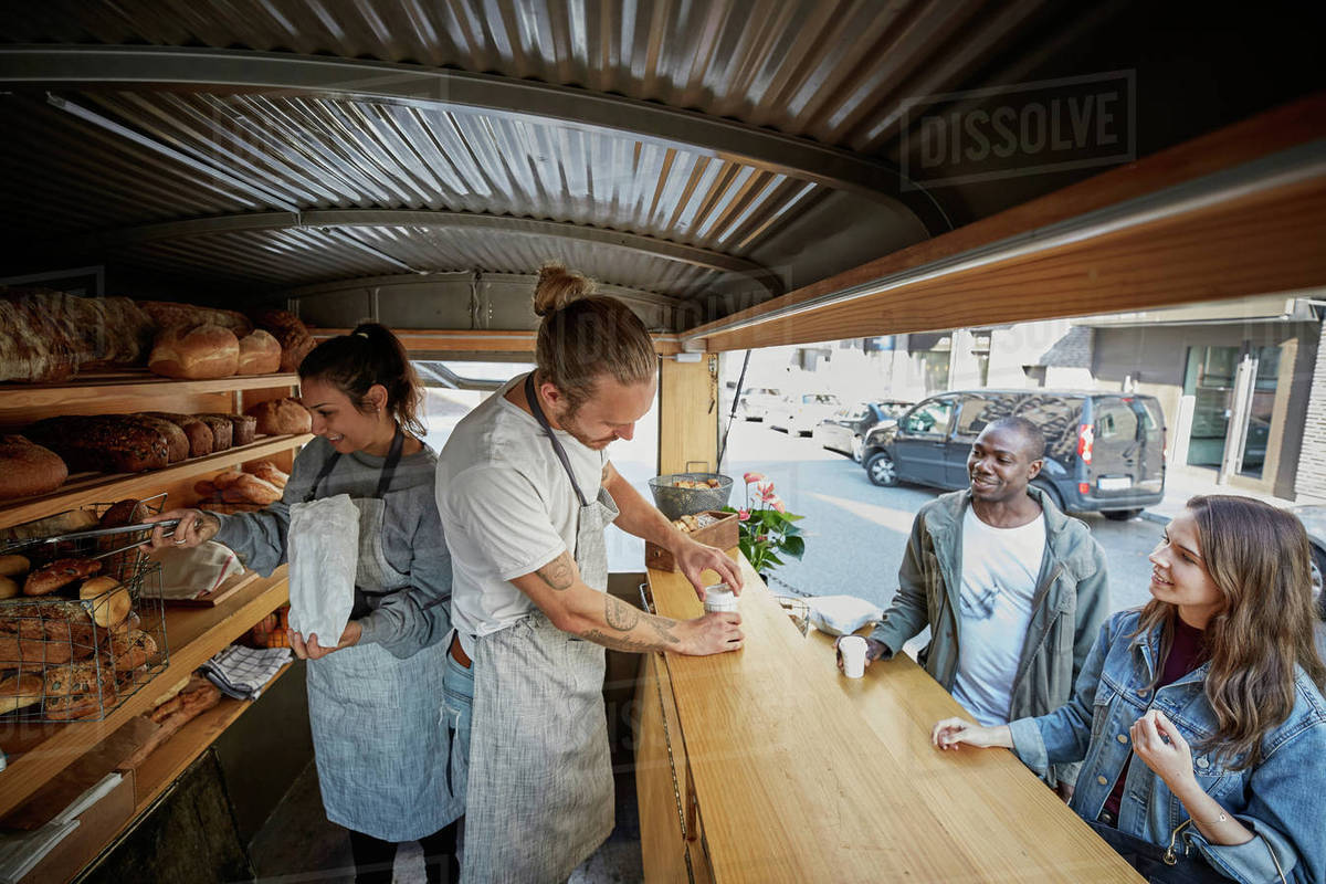 Male and female owners packing food and drink for customers at ...