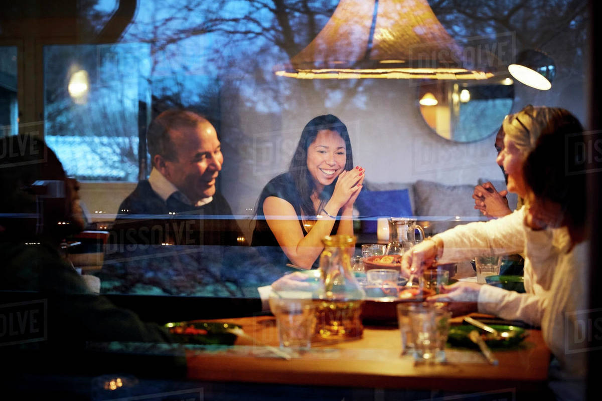 Multi-generation family enjoying dinner at table seen through glass ...