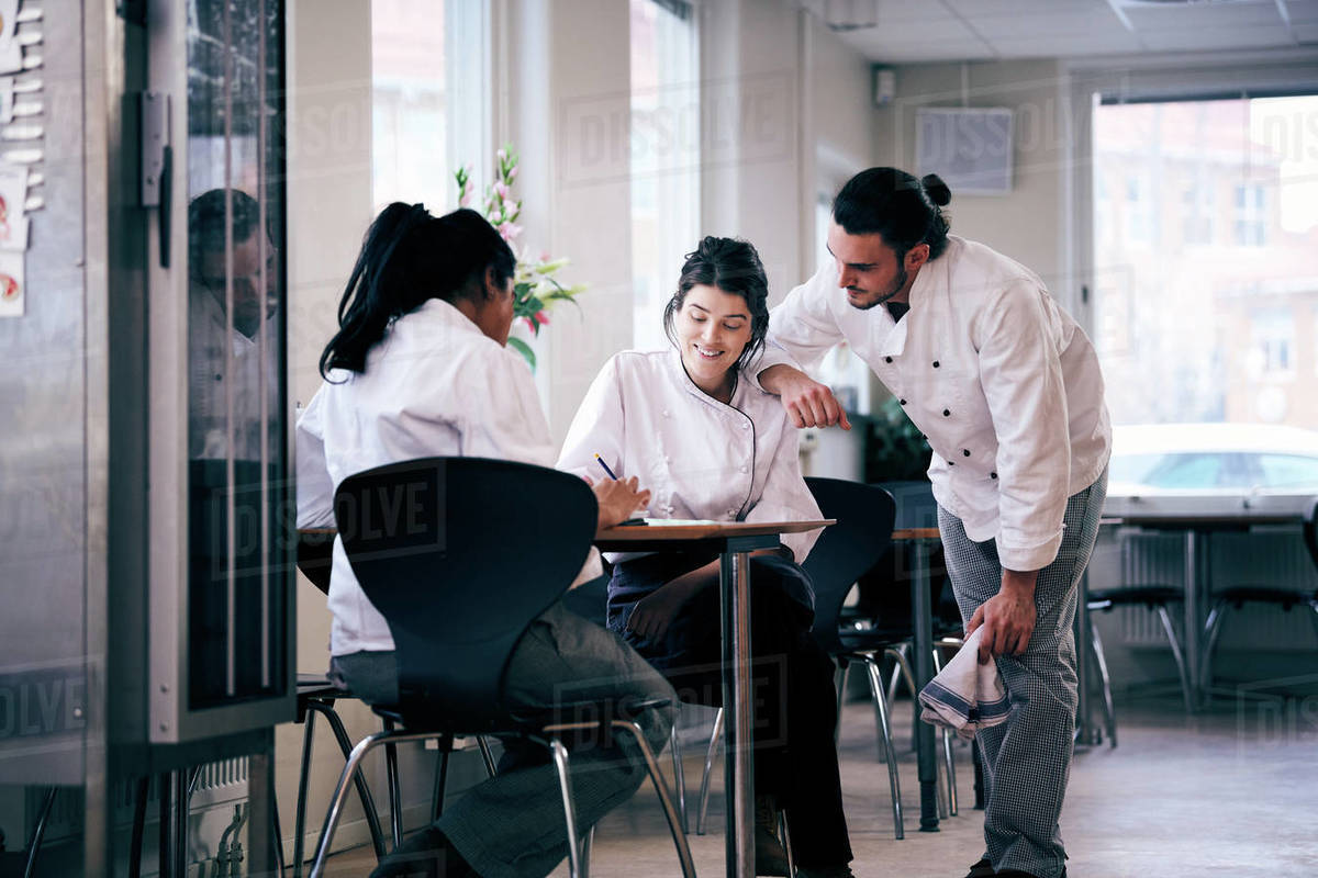 Multi-ethnic male and female chefs discussing menu in restaurant ...