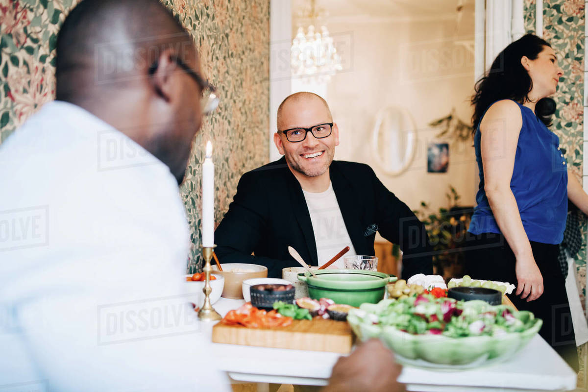 Mature men having dinner at table with female friend standing in ...