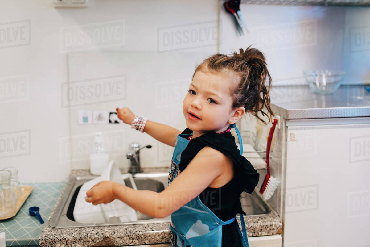 Side view of girl washing utensil in sink at child care - Stock Photo ...