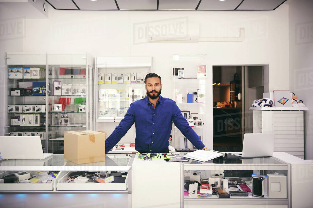 Portrait of confident owner standing at counter in electronics store ...