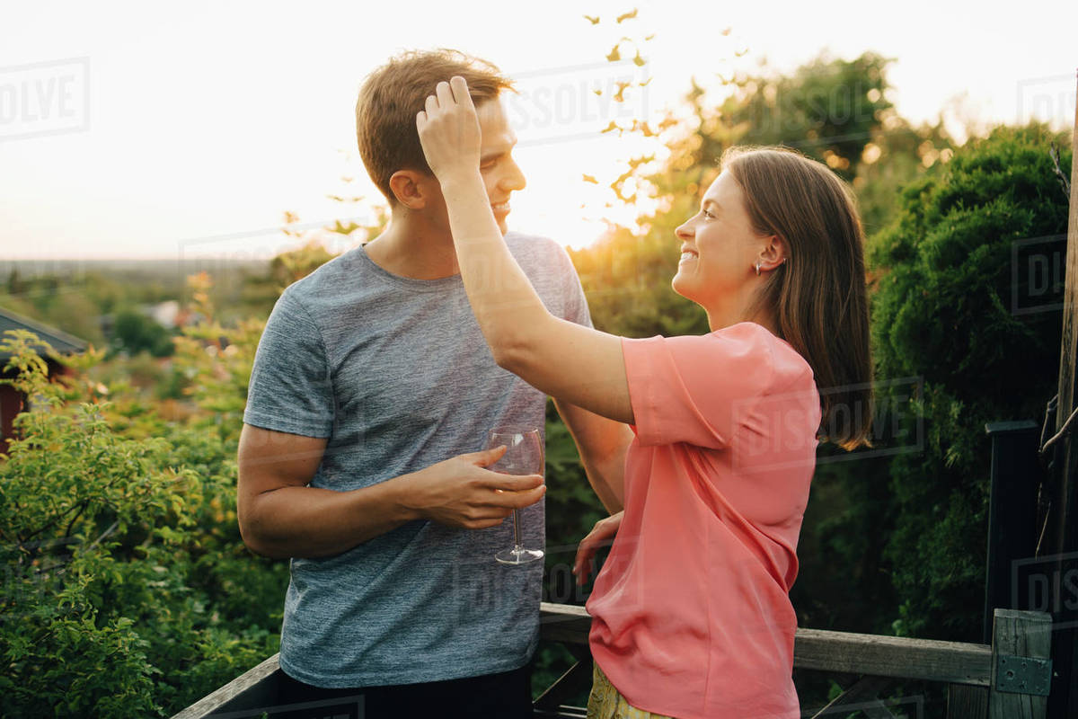 Smiling couple talking while standing at balcony in yard - Royalty-free ...