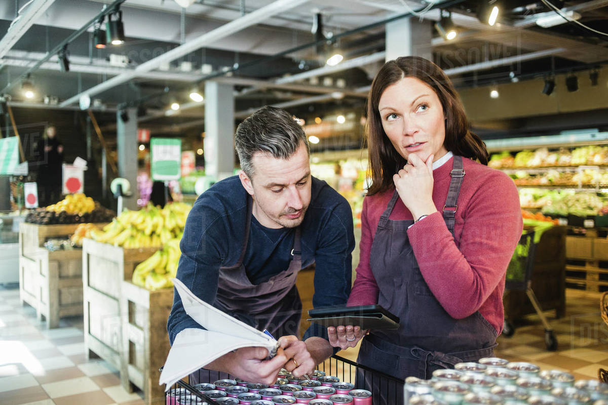 Salesman looking at digital tablet by thoughtful colleague in ...
