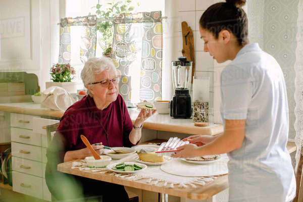 Female healthcare worker explaining medicine to senior woman eating ...
