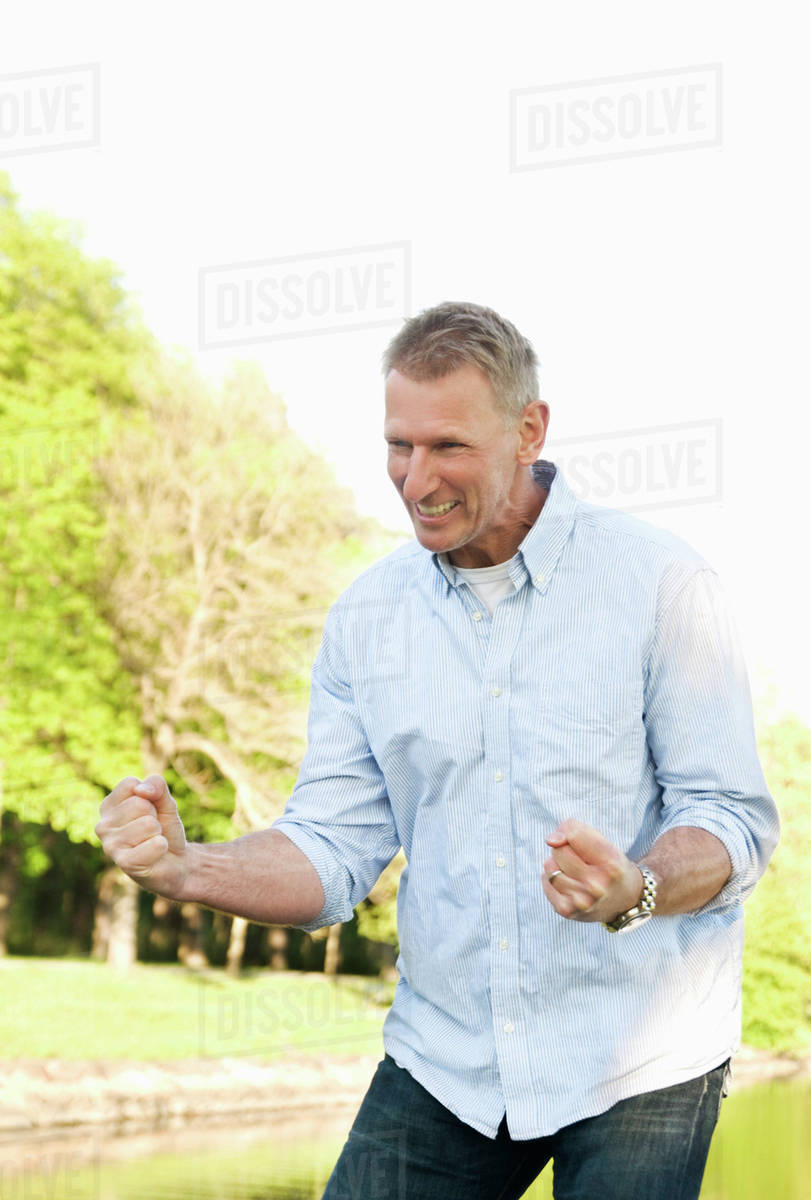 Happy man standing by pond - Stock Photo - Dissolve