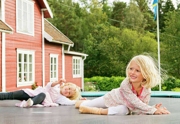 Two sisters lying on rebouncer - Stock Photo - Dissolve