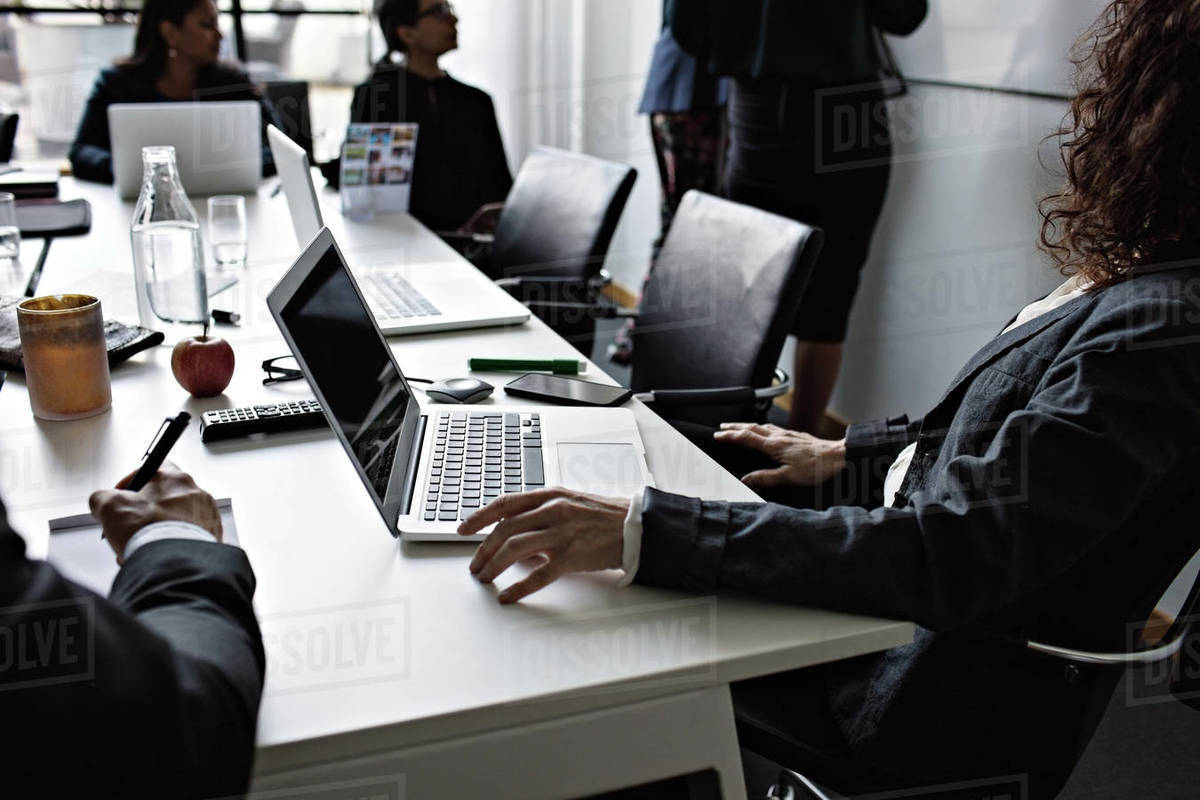 Business people sitting at conference table by female colleagues ...
