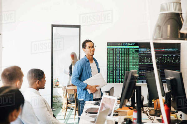 Computer hacker explaining code on television screen to programmers ...