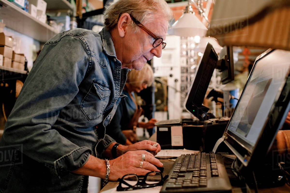 Side view of confident salesman in denim shirt using computer at ...