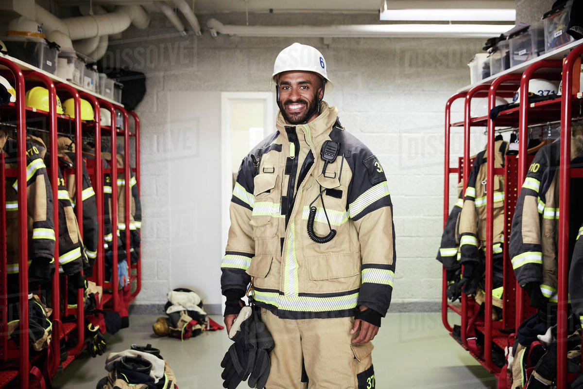 Portrait of smiling male firefighter in locker room at fire station ...