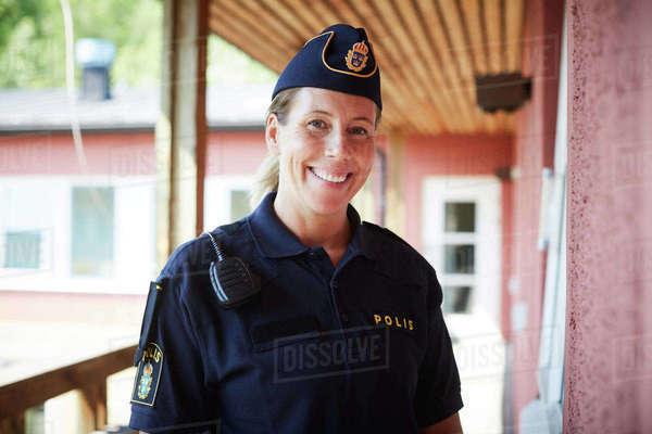 Portrait of smiling policewoman wearing cap standing in balcony at ...