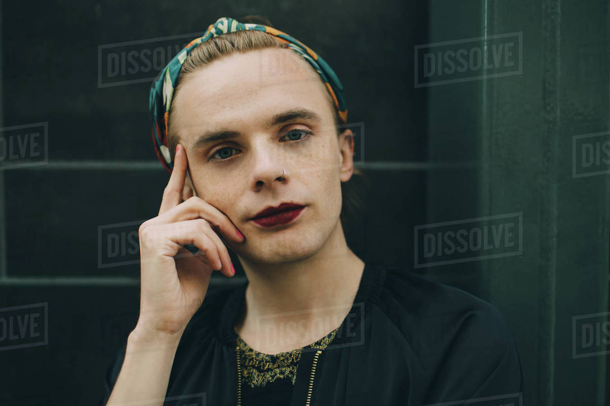 Portrait of young man contemplating while standing against wall ...