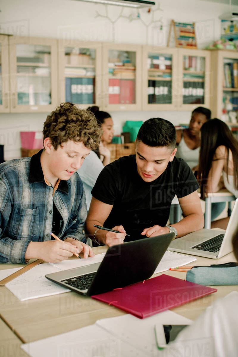 Male students studying while female friends sitting in background ...