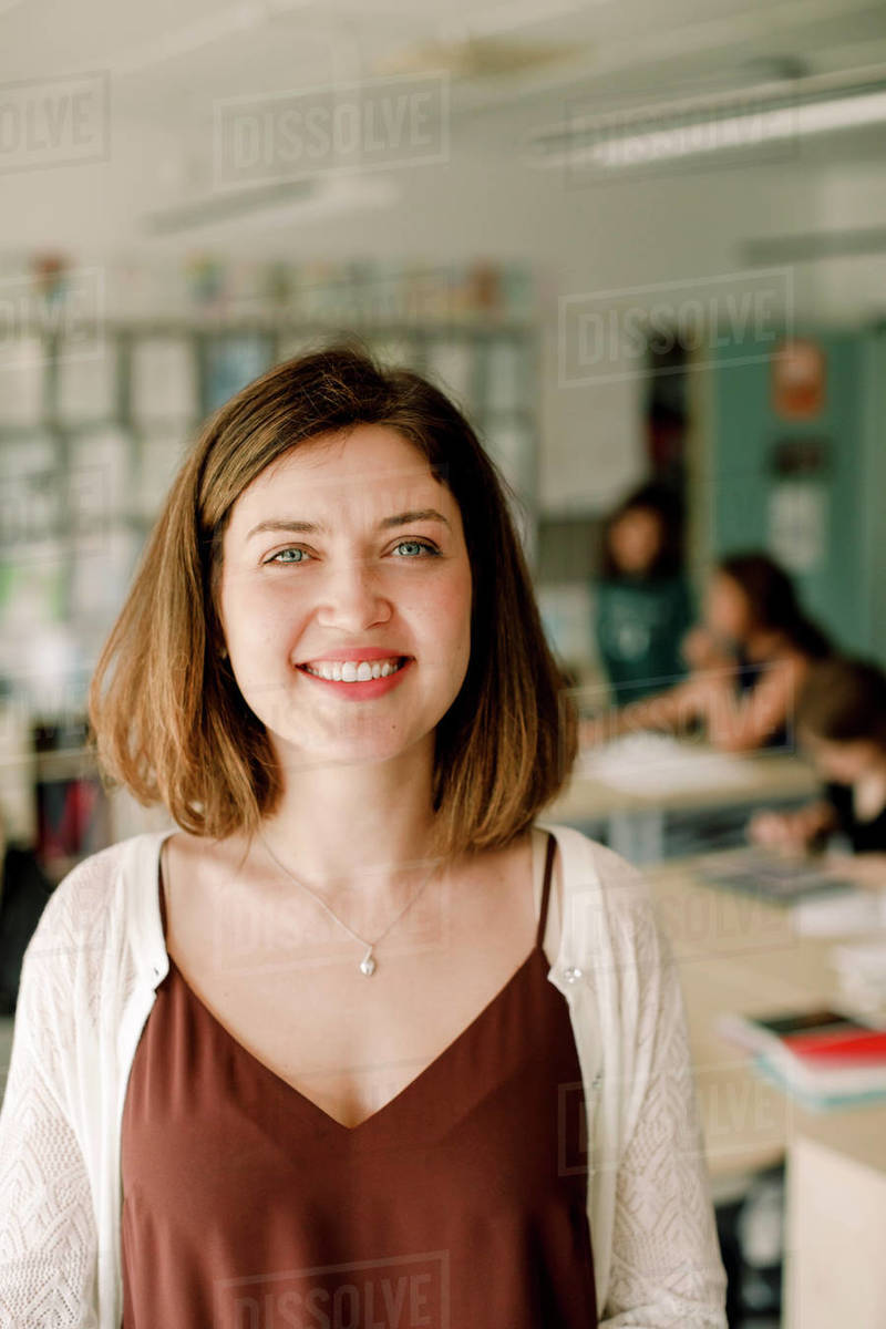Portrait of smiling female tutor standing in classroom - Stock Photo ...
