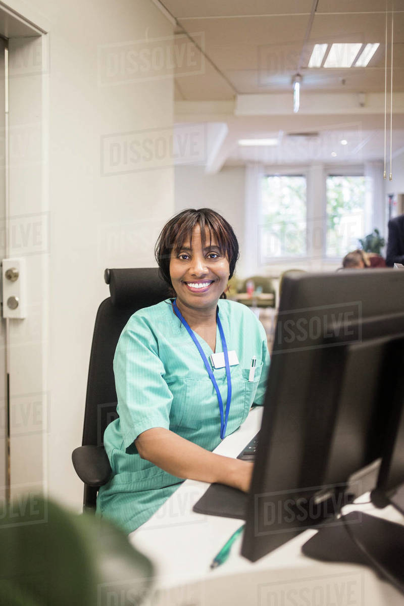 Portrait of smiling female doctor with bangs working on computer while ...