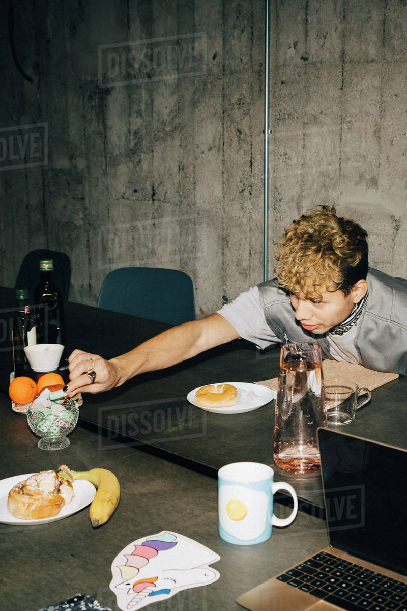 Man eating candy at table in office - Royalty-free Stock Photo | Dissolve
