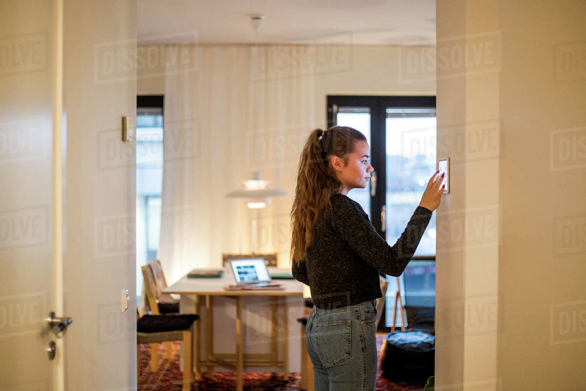 Teenage girl using digital tablet mounted on wall at home - Royalty ...