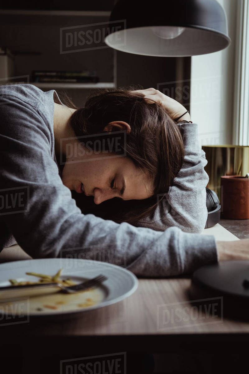 Side view of sad woman at table - Royalty-free Stock Photo | Dissolve