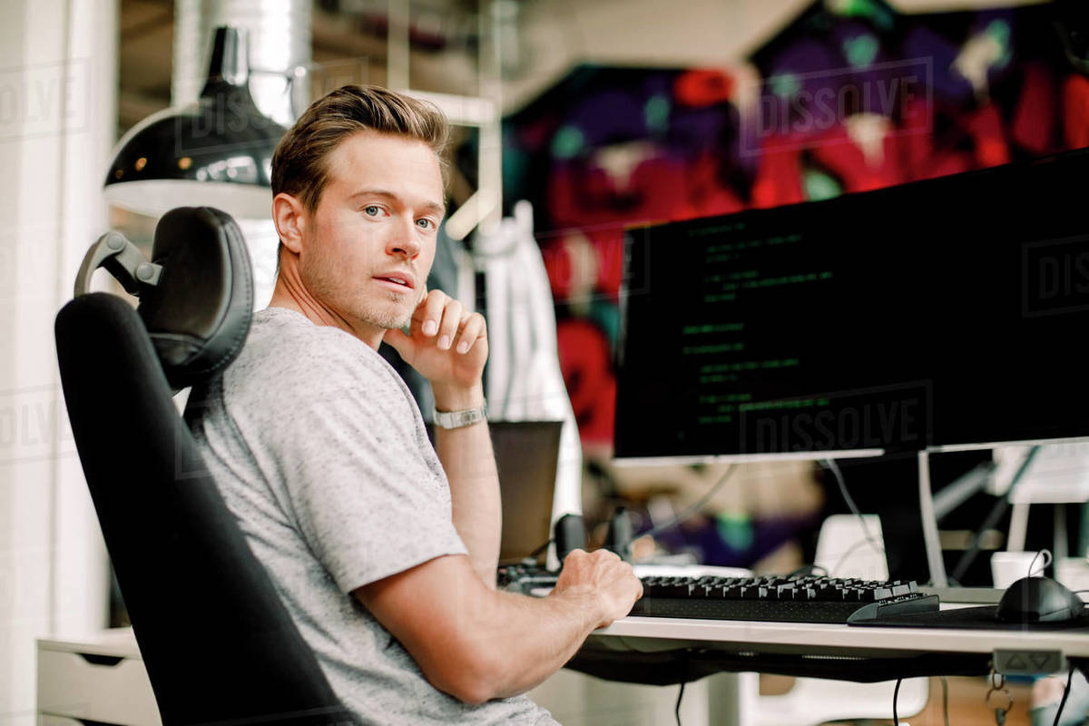 Portrait of male computer programmer sitting in office - Stock Photo - Dissolve