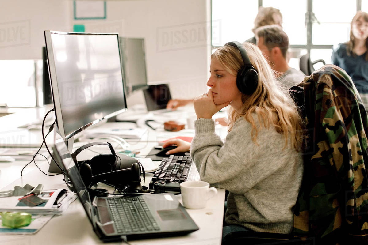 Female colleague looking at computer while working in office - Stock ...