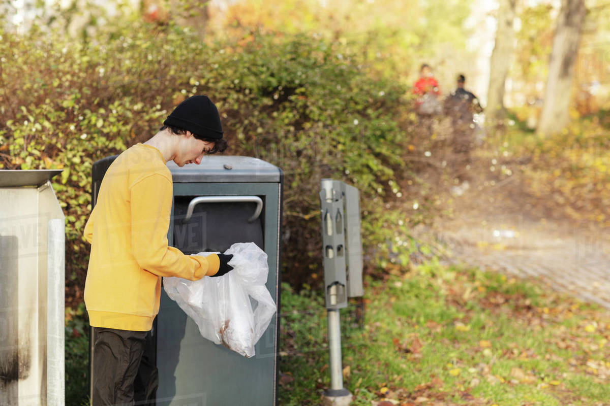 Male volunteer throwing plastic waste in garbage can - Royalty-free ...